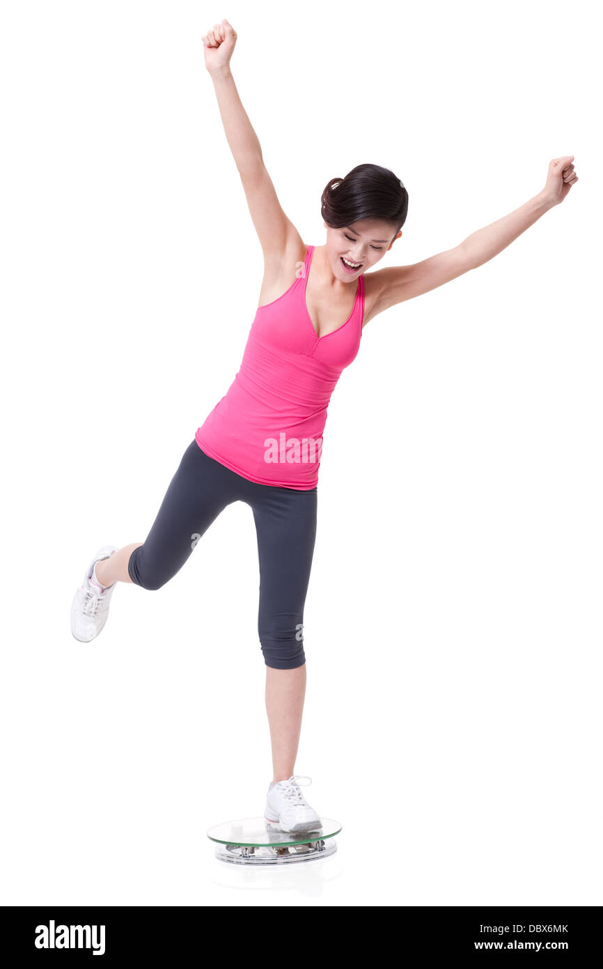 Slim young woman standing on scale and cheering Stock Photo - Alamy
