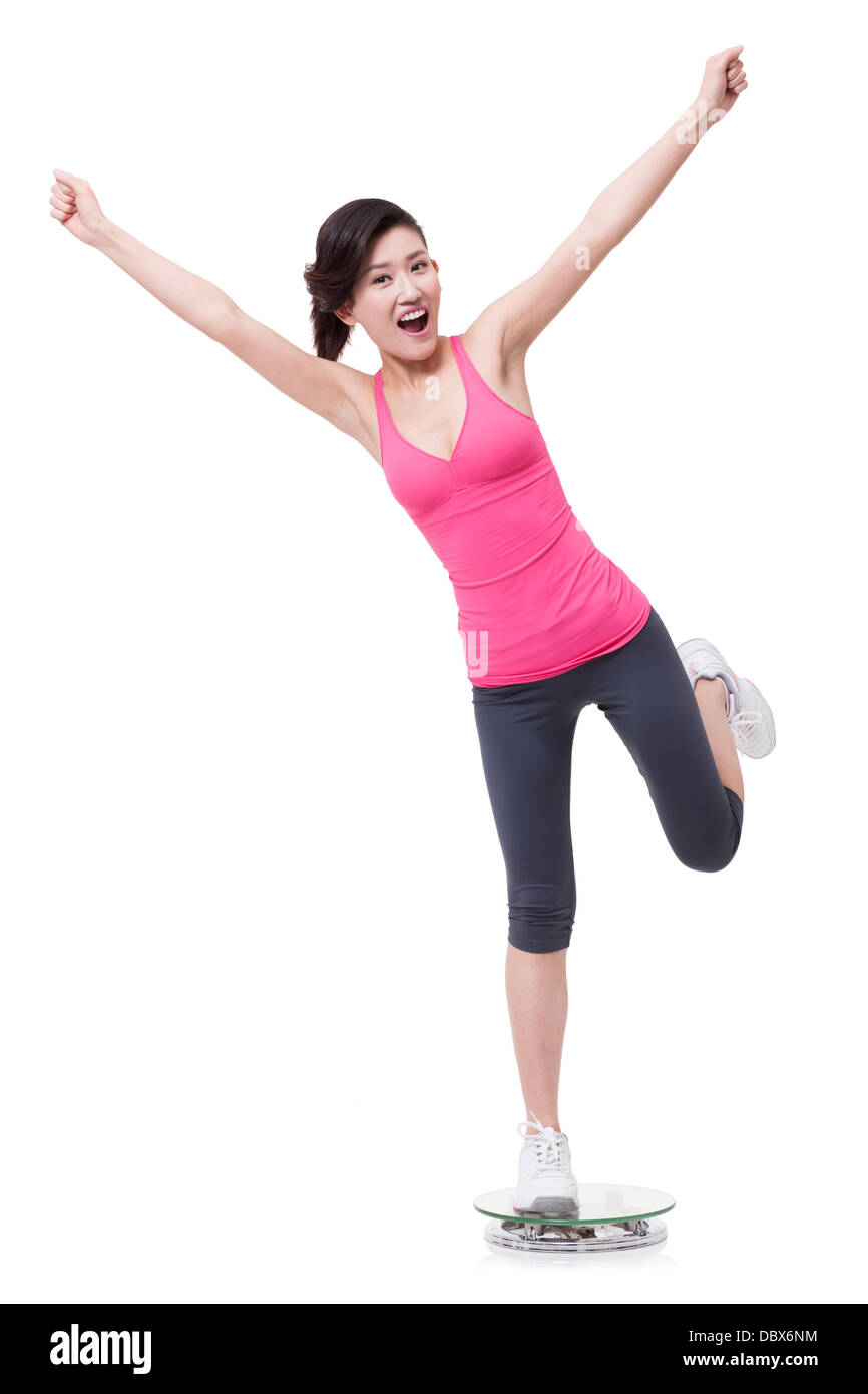 Slim young woman standing on scale and cheering Stock Photo - Alamy