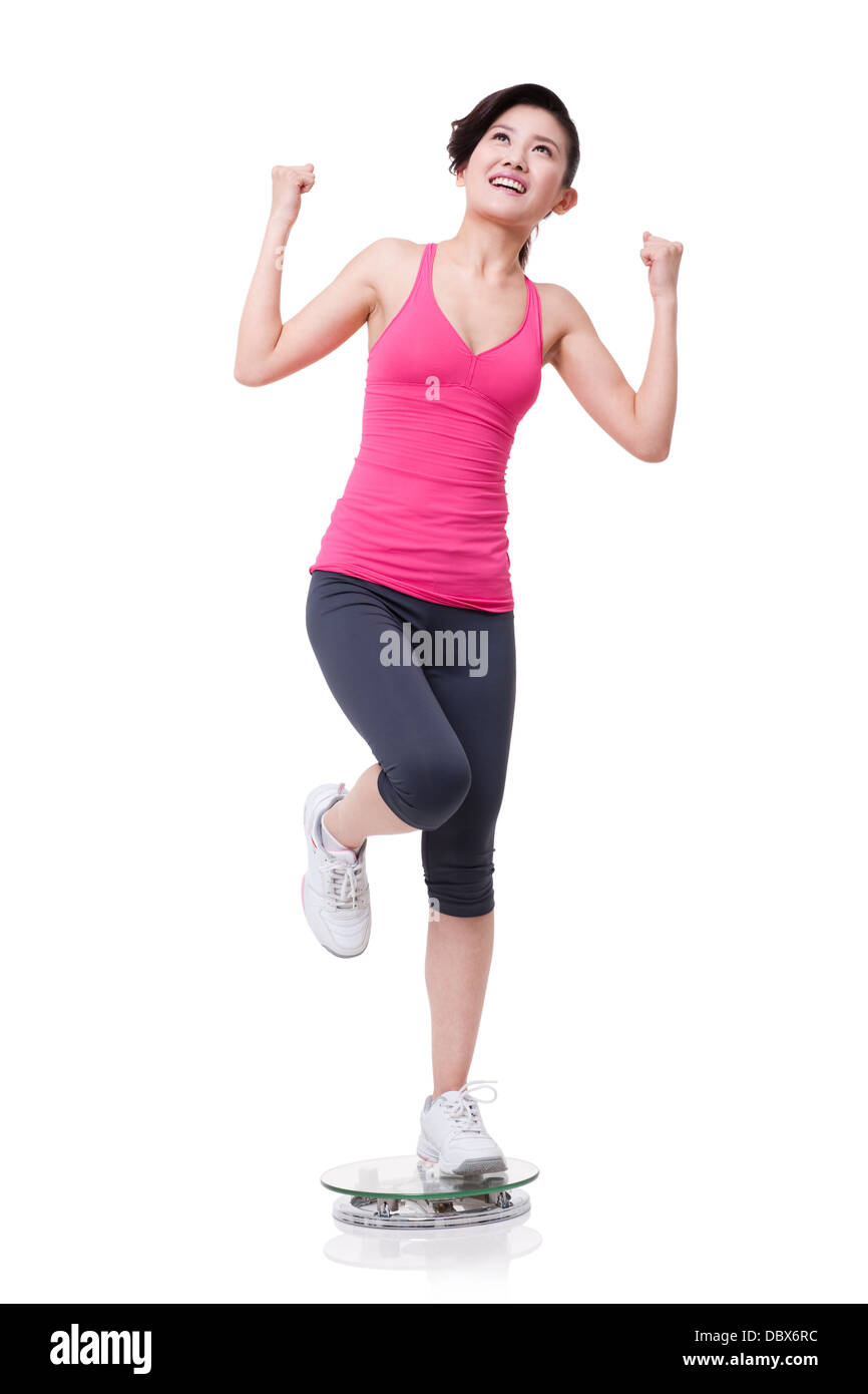 Slim young woman standing on scale and cheering Stock Photo - Alamy
