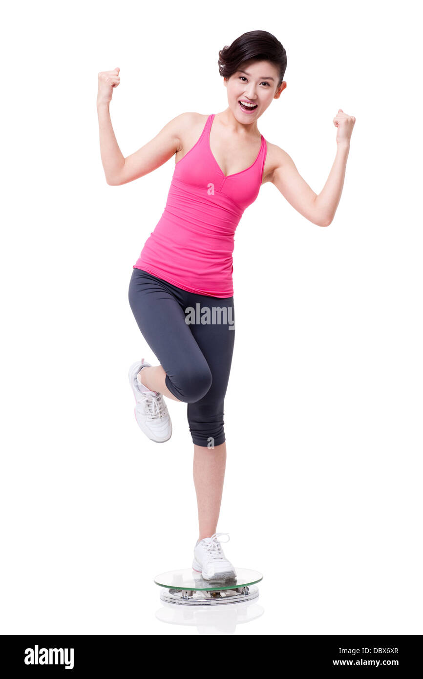 Slim young woman standing on scale and cheering Stock Photo - Alamy