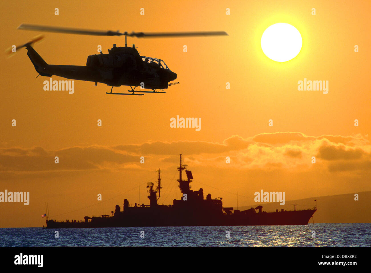 2000s USMC AH-1 SEA COBRA HELICOPTER FLYING AT SUNSET PAST USN WARSHIP ...