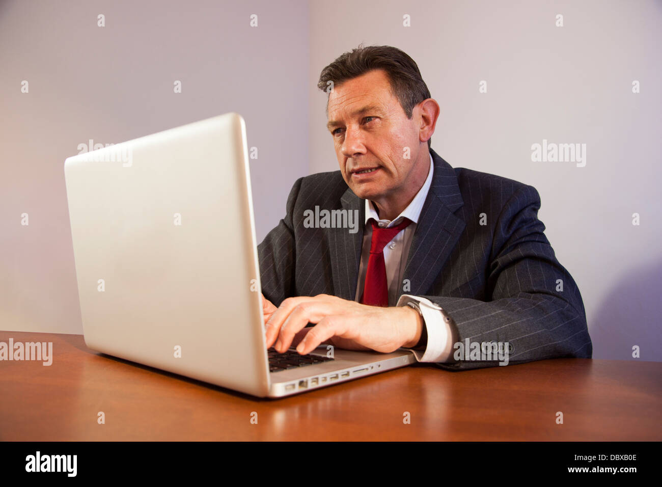 Mature business man at a desk using a laptop computer Stock Photo - Alamy