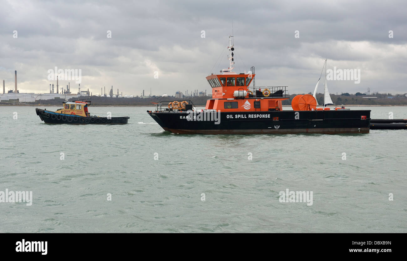 oil spill response containment vessels towing boom in front of refinery ...