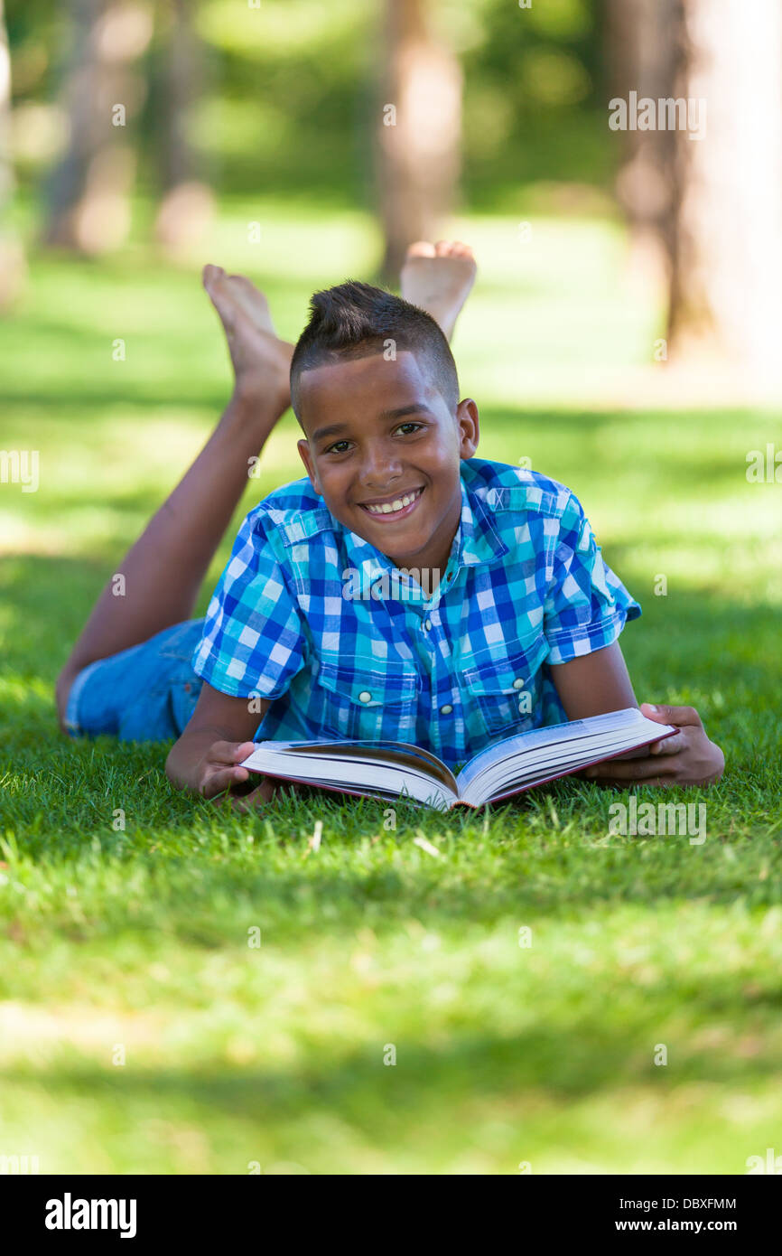 Outdoor portrait of student black boy reading a book - African people ...