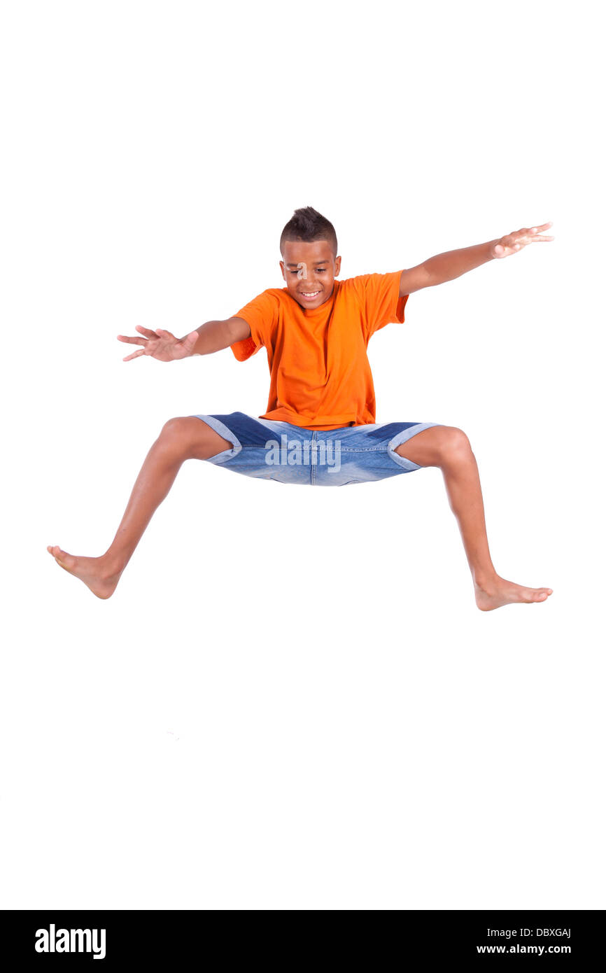 Portrait of a cute teenage black boy jumping over white background ...