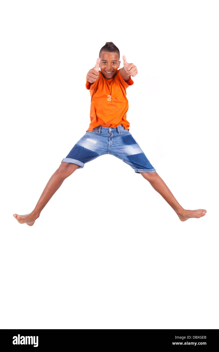 Portrait of a cute teenage black boy jumping over white background ...