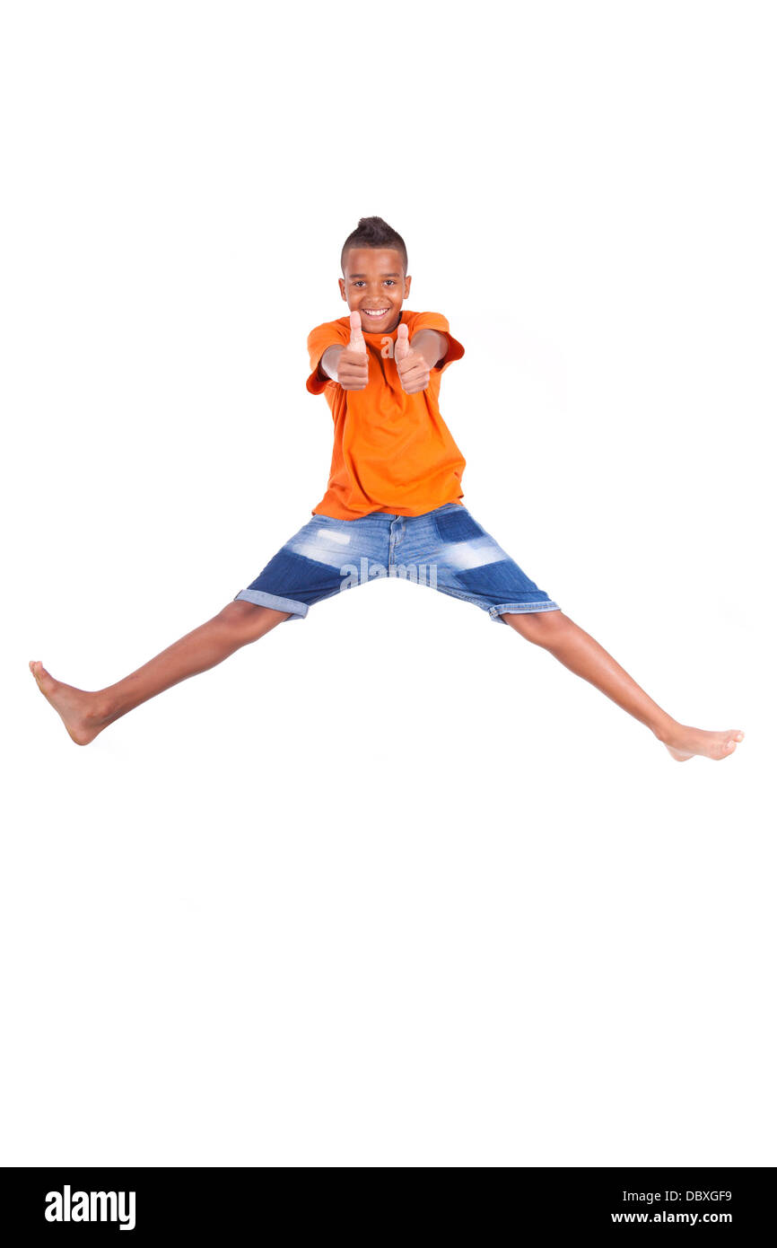 Portrait of a cute teenage black boy jumping over white background ...