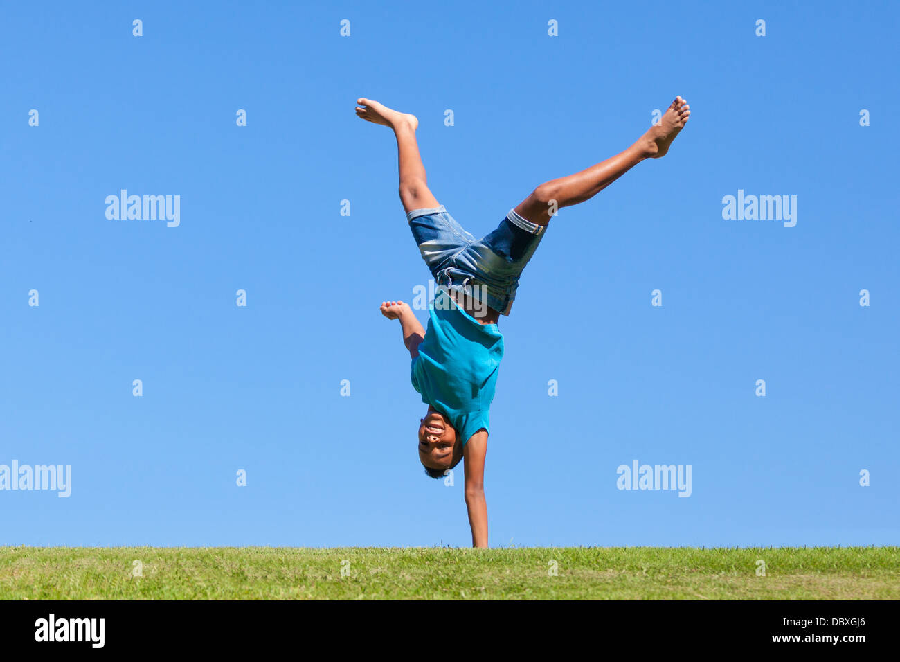 Outdoor portrait of a cute teenage black boy jumping over a blue sky ...