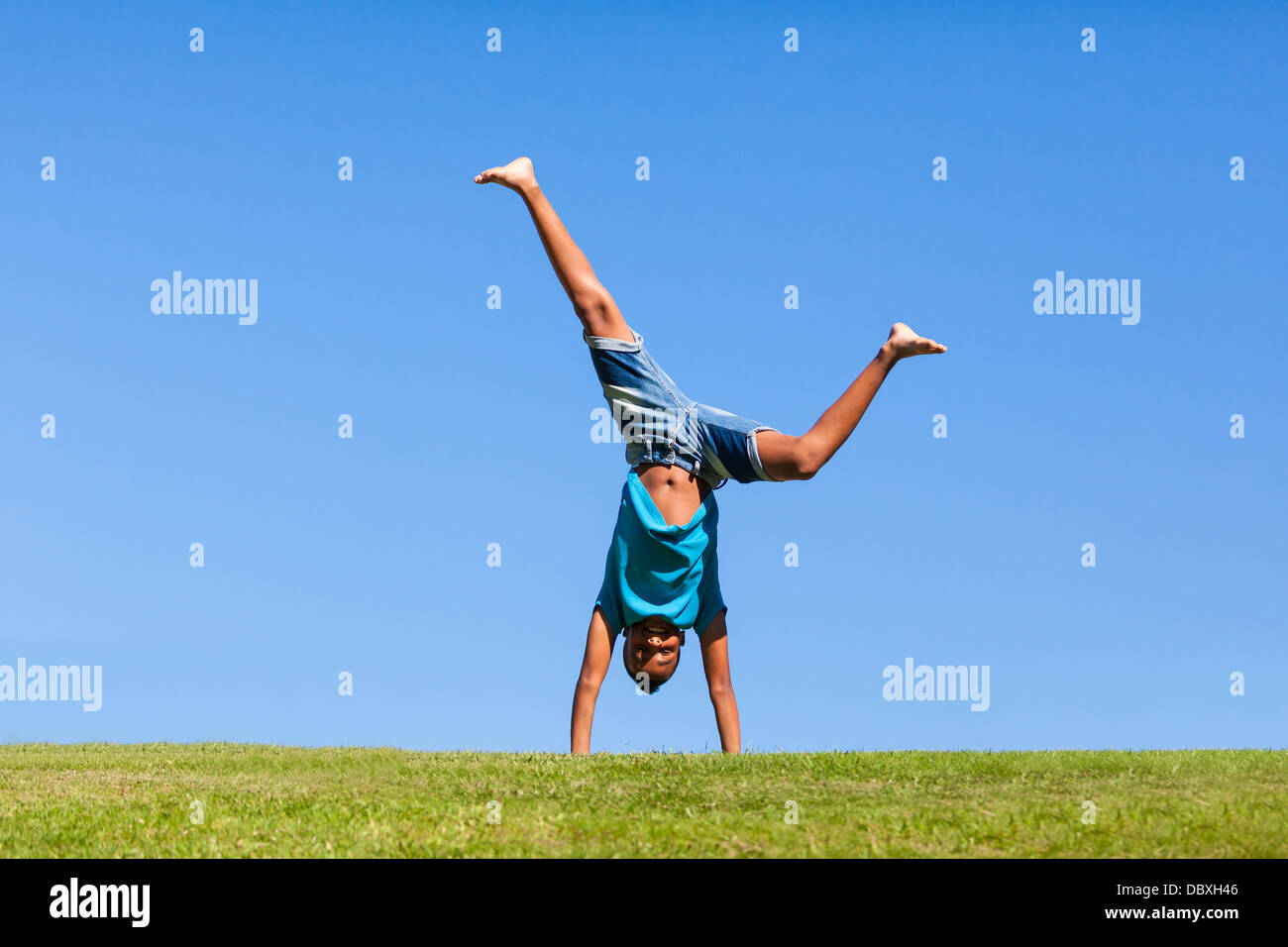 Outdoor portrait of a cute teenage black boy jumping over a blue sky ...