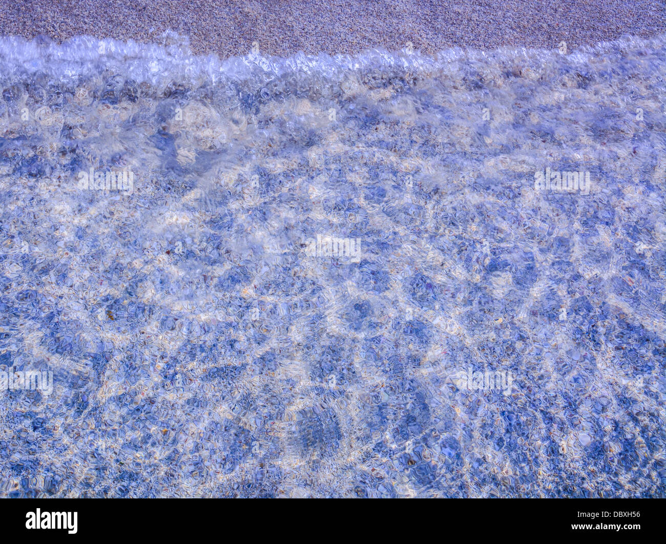 Shallow transparent water surface with small seashells and rocks as ...