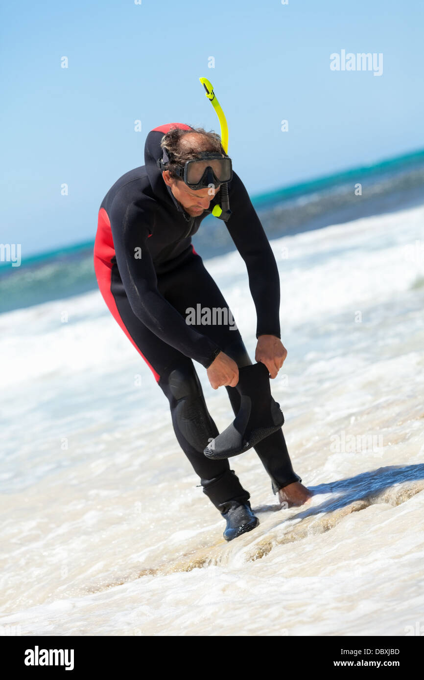 male diver with diving suit snorkel mask fins on the beach in Summer ...