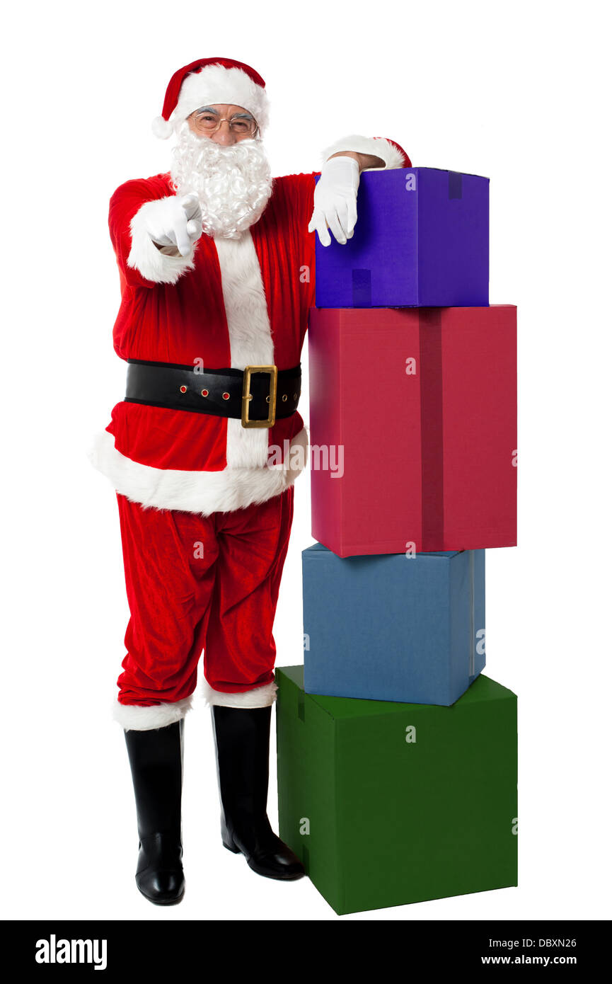 Smiling senior Santa posing beside colorful stack of Xmas presents ...