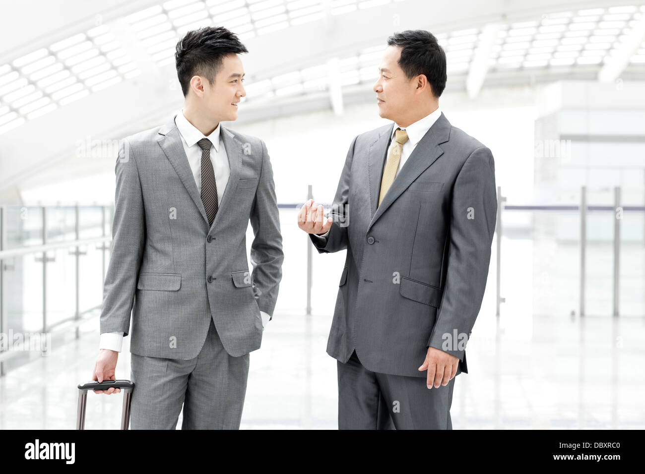 Standing side by side communication smiling gesturing hands in pockets ...