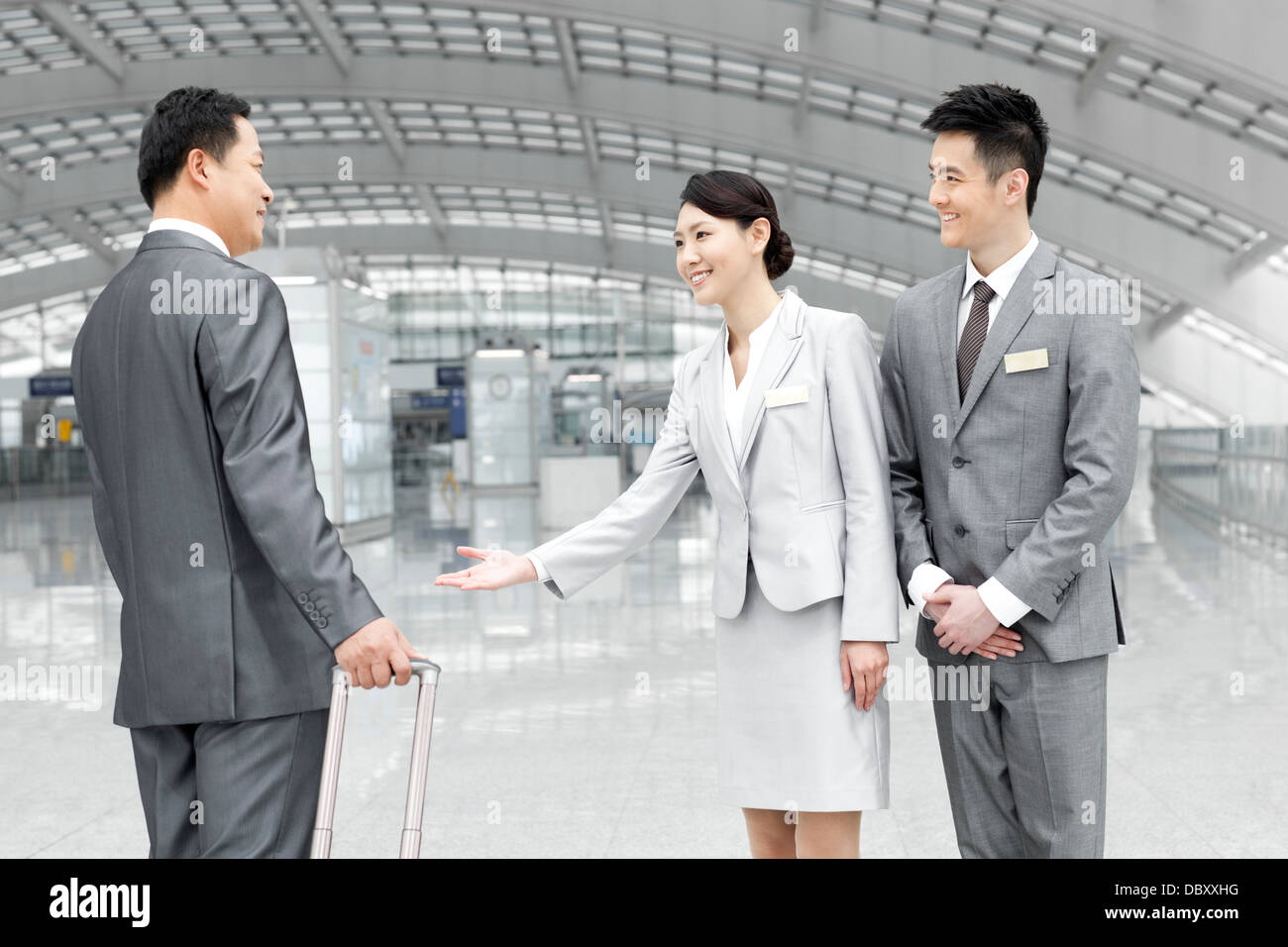 Airport staff members welcoming passenger in airport lobby Stock Photo ...