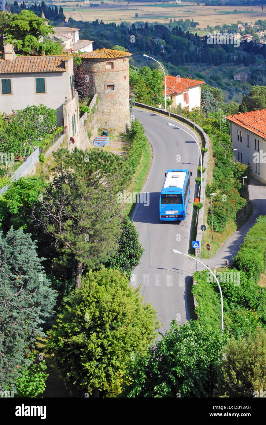 A bus on a winding road approaching Pienza in the Tuscan Hills of Italy ...