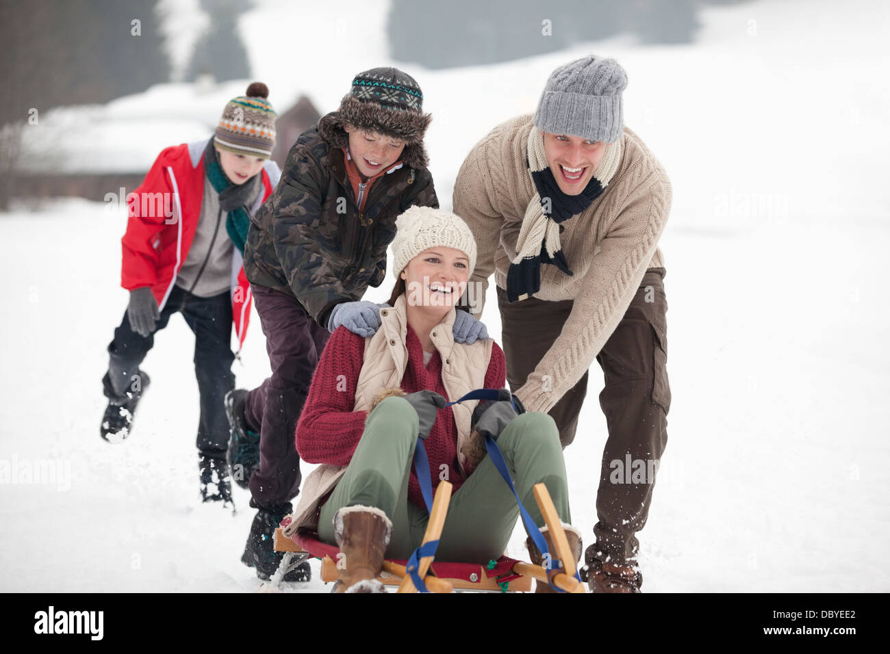 Happy family sledding in snowy field Stock Photo - Alamy