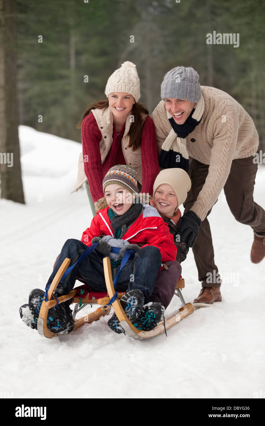 Happy family sledding in snowy woods Stock Photo - Alamy