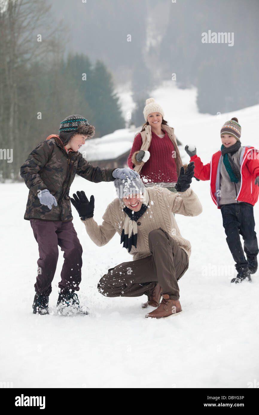 Happy family enjoying snowball fight in field Stock Photo - Alamy
