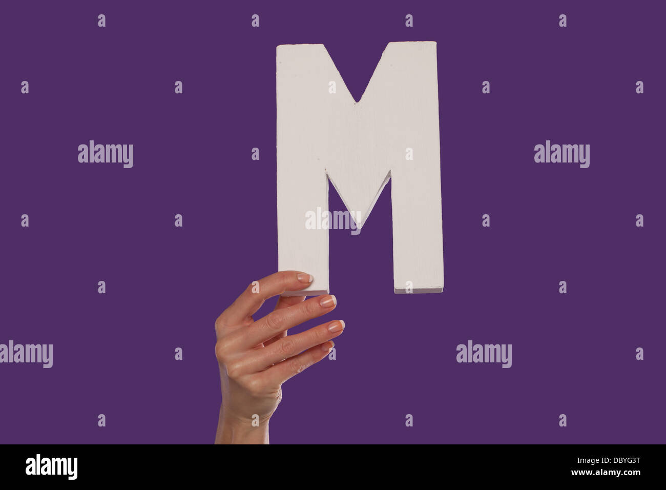 Female hand holding up the letter M from the bottom Stock Photo - Alamy