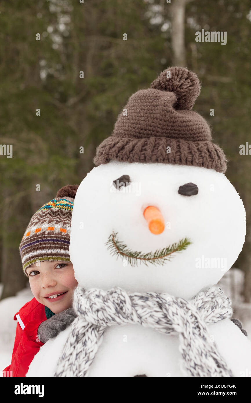 Portrait of smiling boy behind snowman with stocking-cap Stock Photo ...