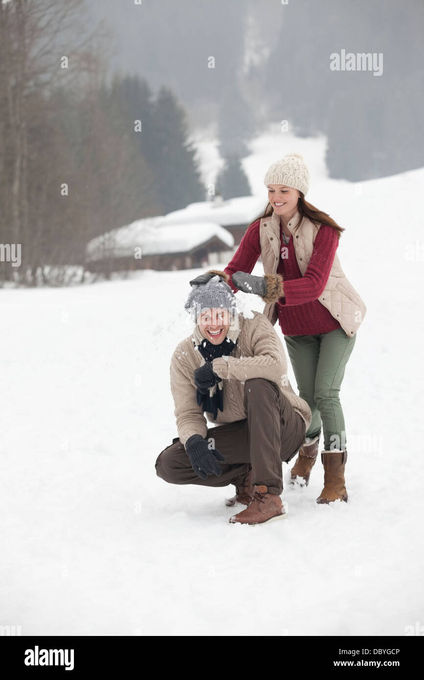 Happy couple enjoying snowball fight in field Stock Photo - Alamy
