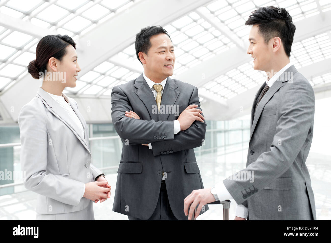 Happy business associates having conversation in airport lobby Stock ...