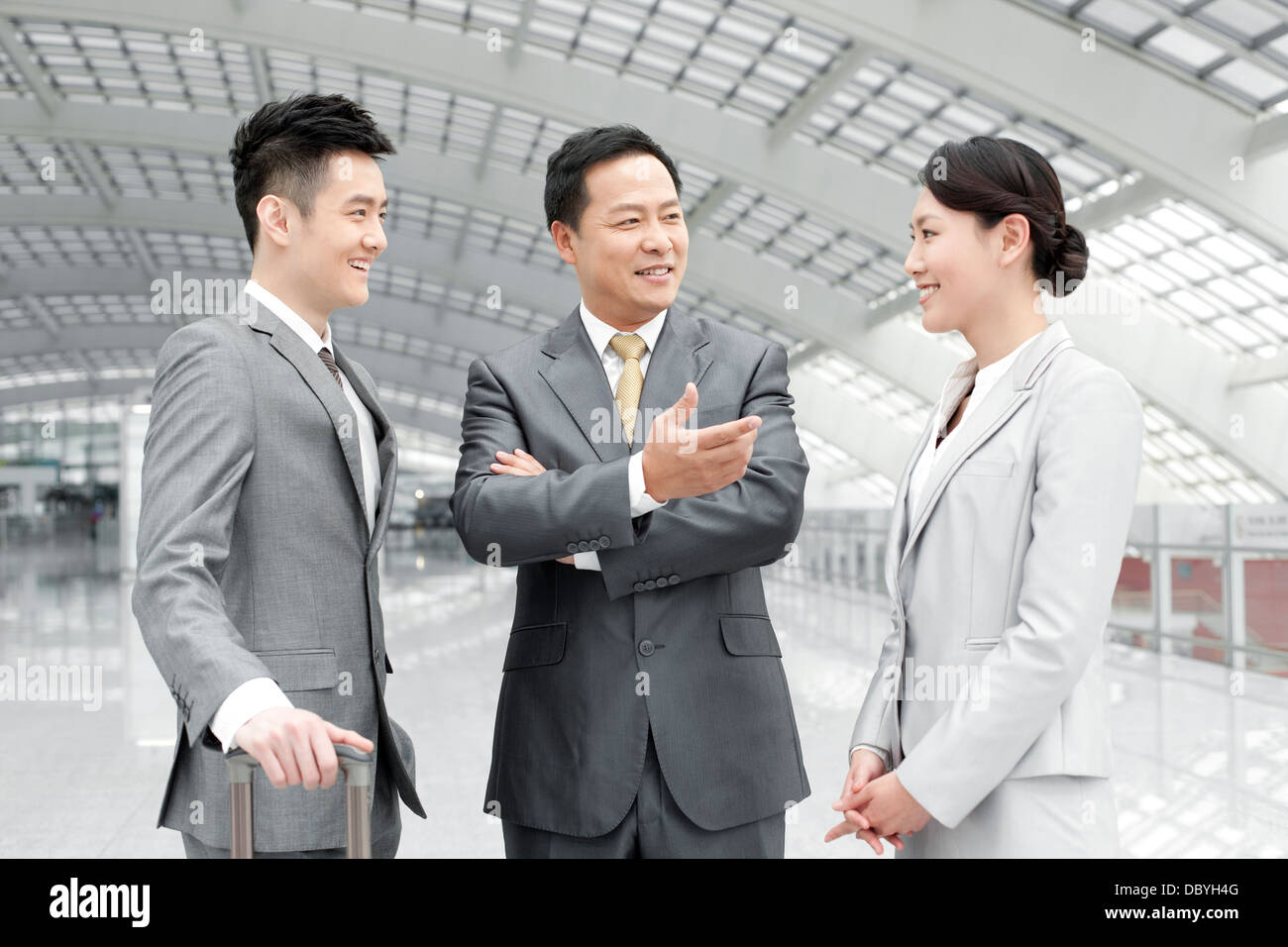 Happy business associates having conversation in airport lobby Stock ...