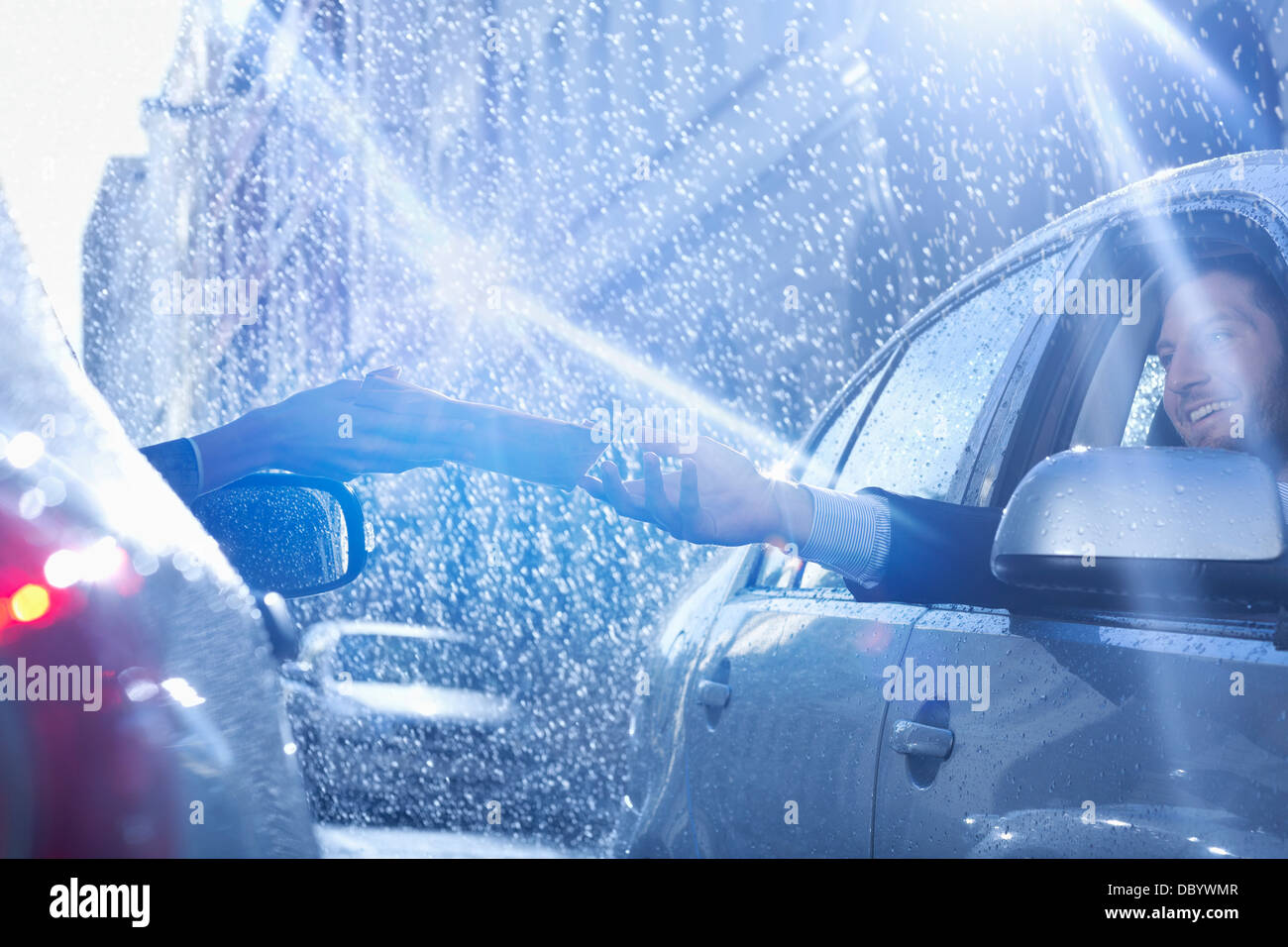 Businessman in car reaching for paperwork in rain Stock Photo - Alamy