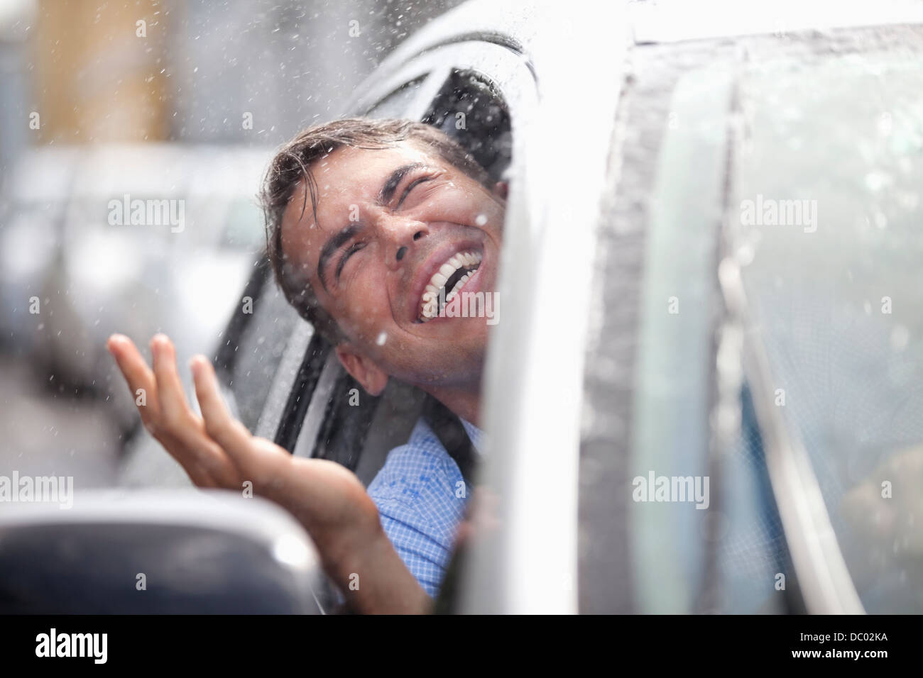 Enthusiastic man in car looking out window at rain Stock Photo - Alamy