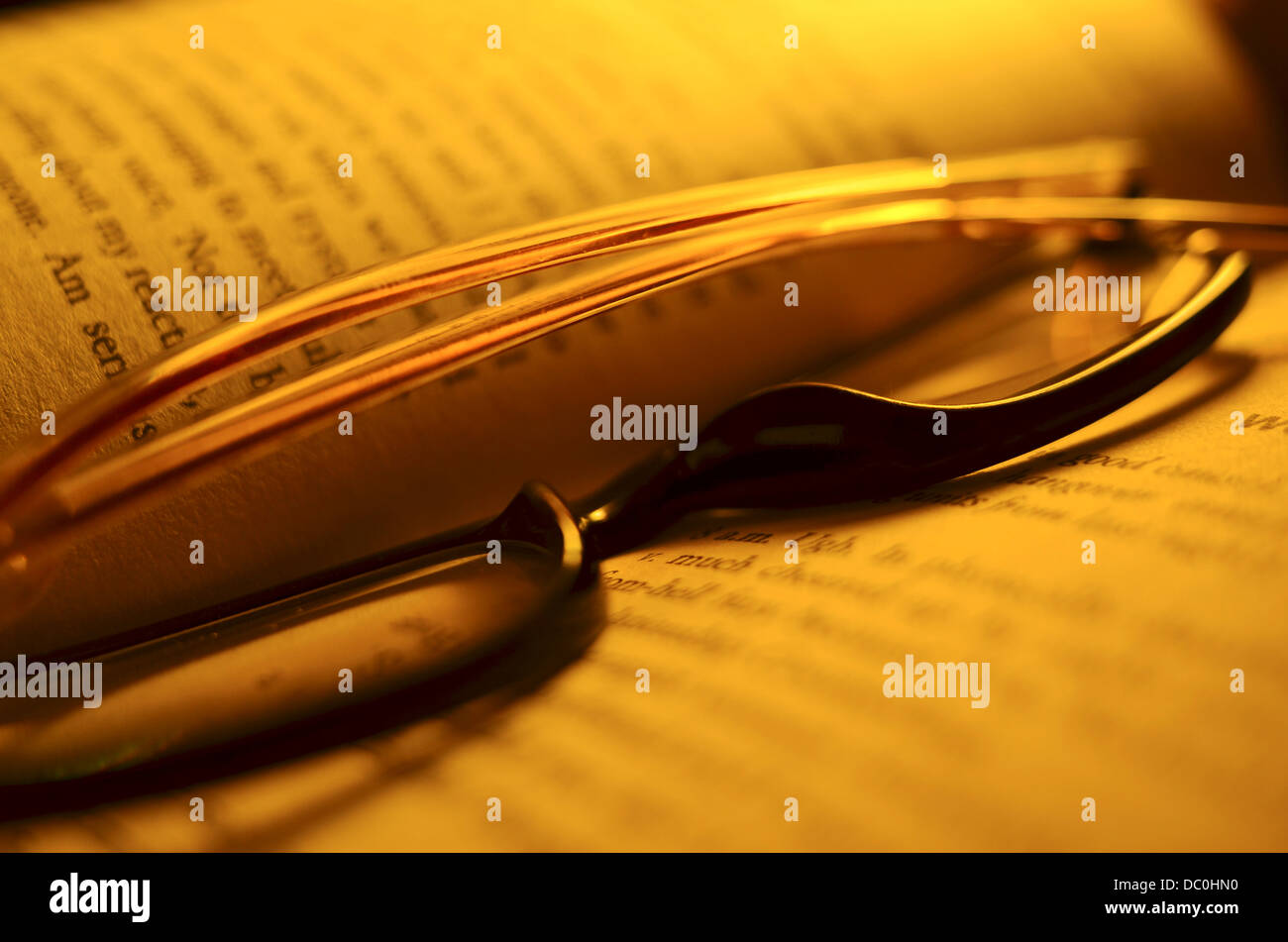 Reading glasses resting on an open book Stock Photo - Alamy