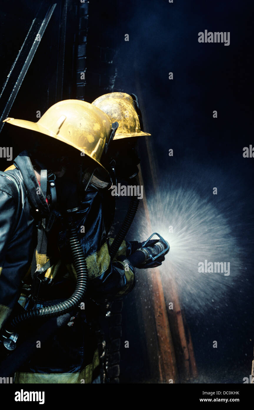 1970s TWO FIREFIGHTERS USE HOSE TO BATTLE FIRE Stock Photo - Alamy
