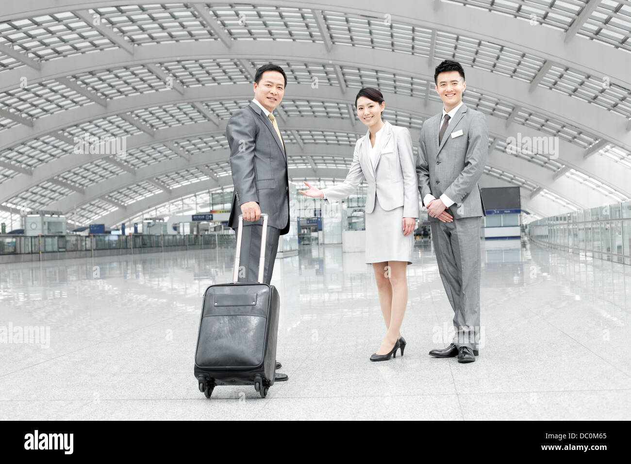 Young business partners with name tags greeting guest at the airport ...