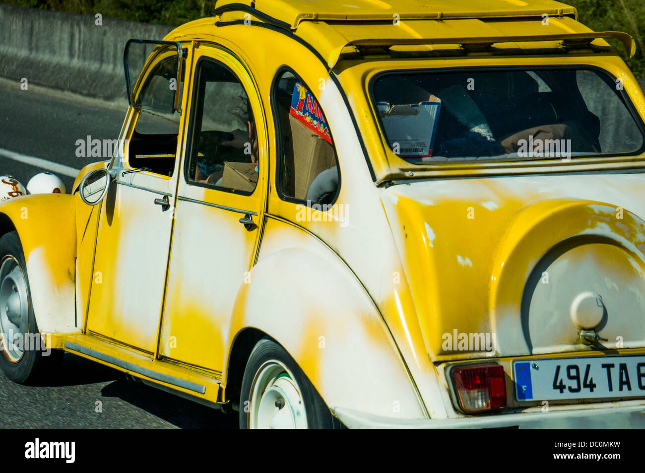 A striking yellow and white, iconic Citroen 2CV car, seen travelling in ...