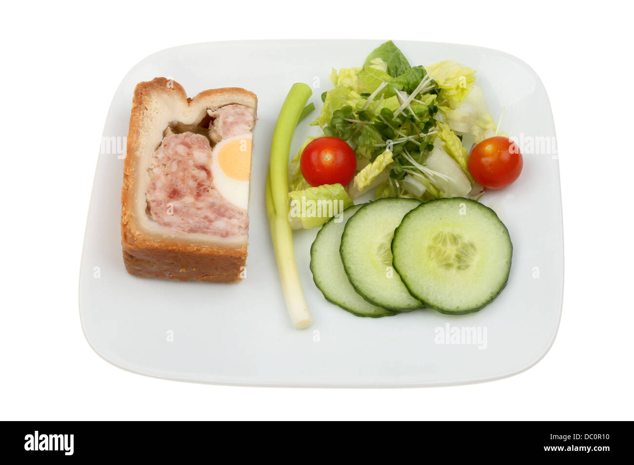 Slice of pork and egg gala pie with a salad garnish on a plate isolated ...