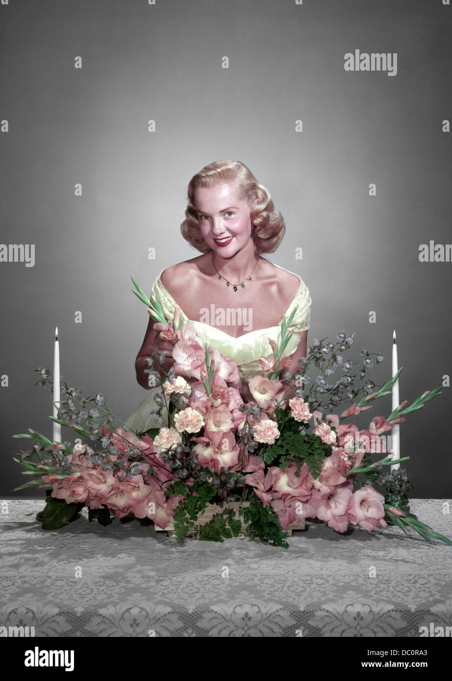 1950s SMILING WOMAN WEARING FORMAL GOWN ARRANGING FLOWERS CENTERPIECE ...