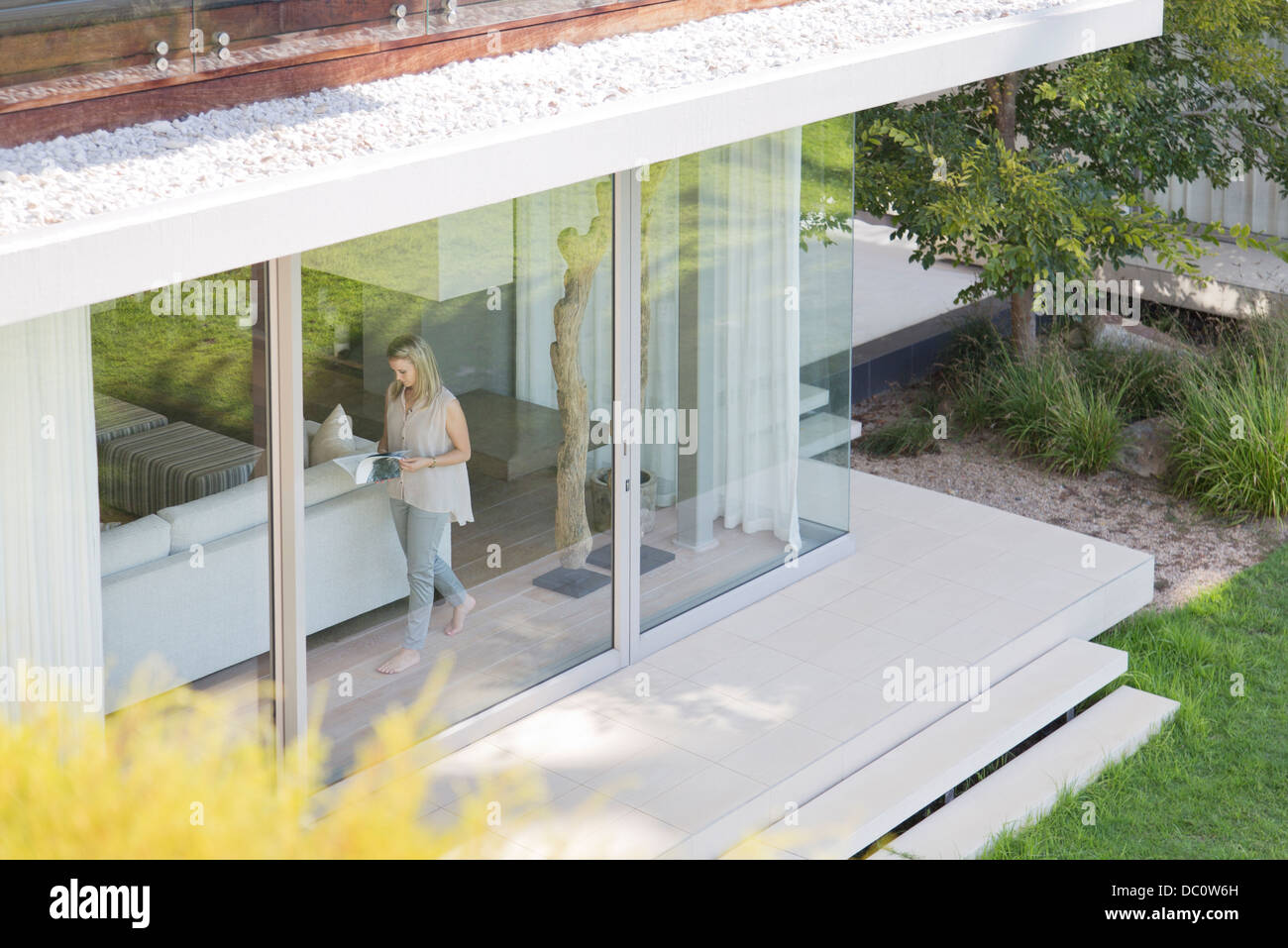 Woman walking along window inside house Stock Photo - Alamy