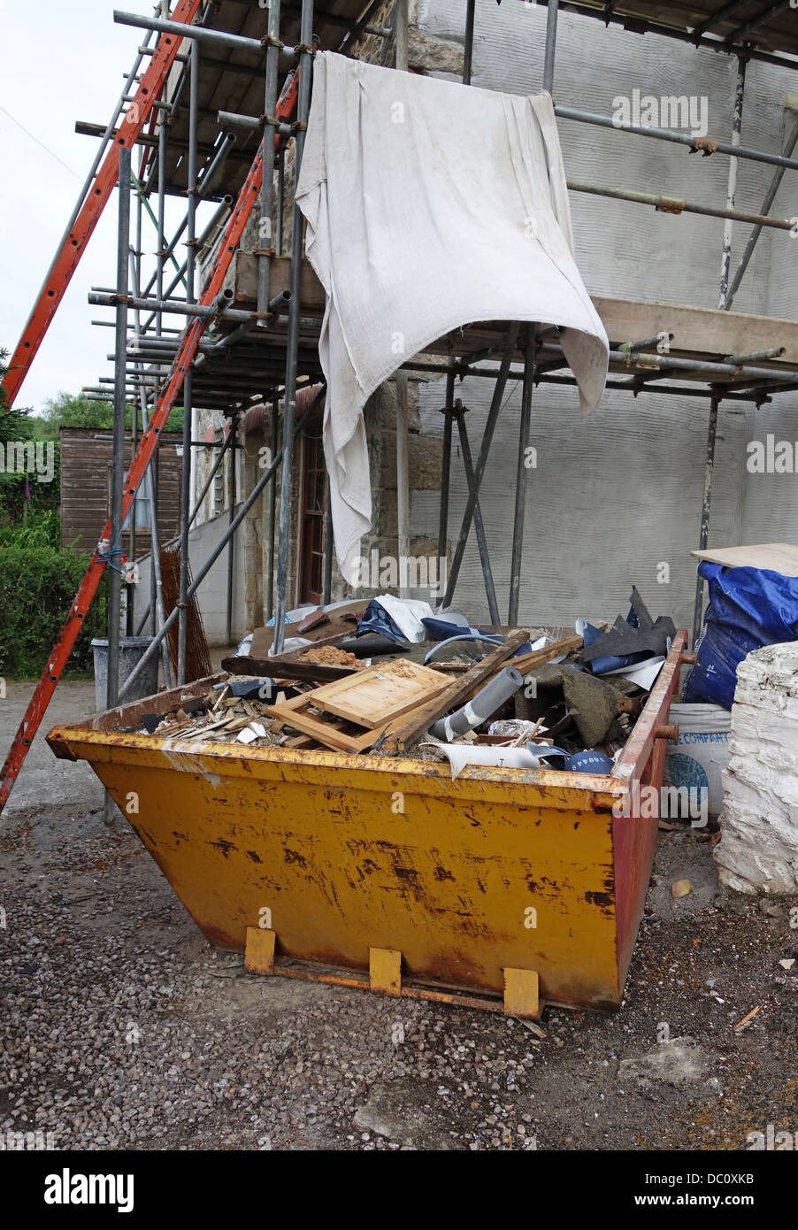 A full builders skip outside a cottage being renovated Stock Photo - Alamy