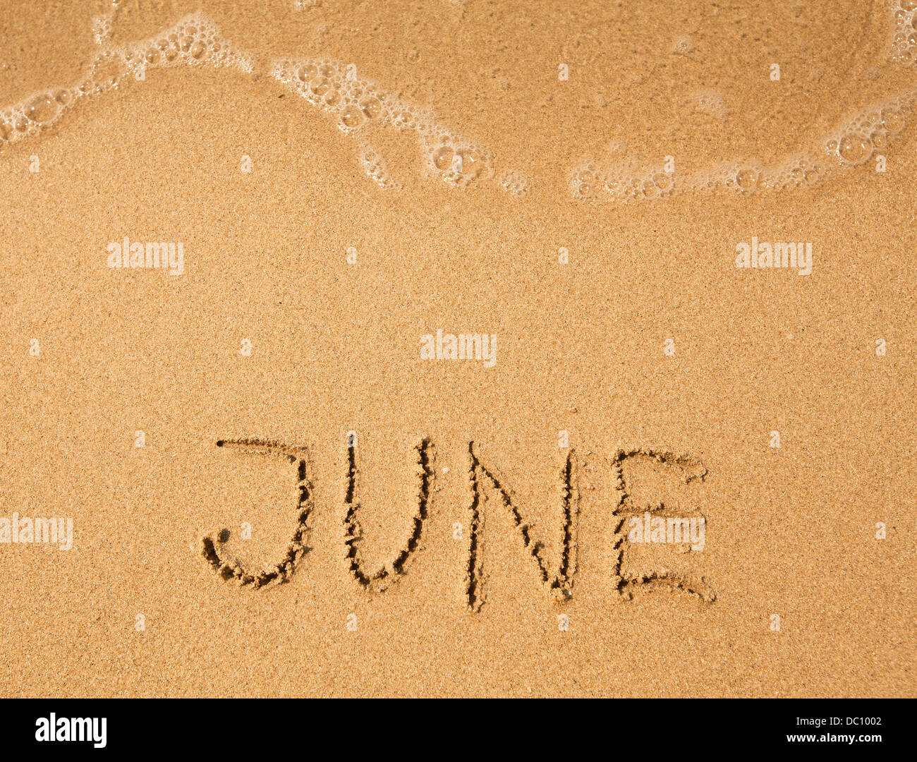 June - written in sand on beach texture (soft wave of the sea Stock ...