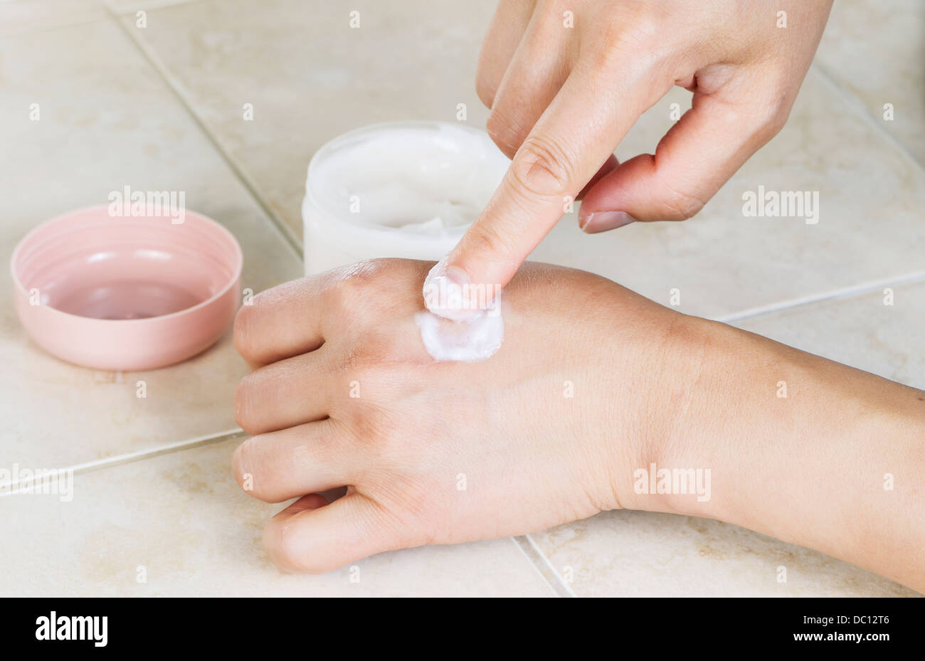 Close up horizontal photo of female index finger rubbing cosmetic cream ...