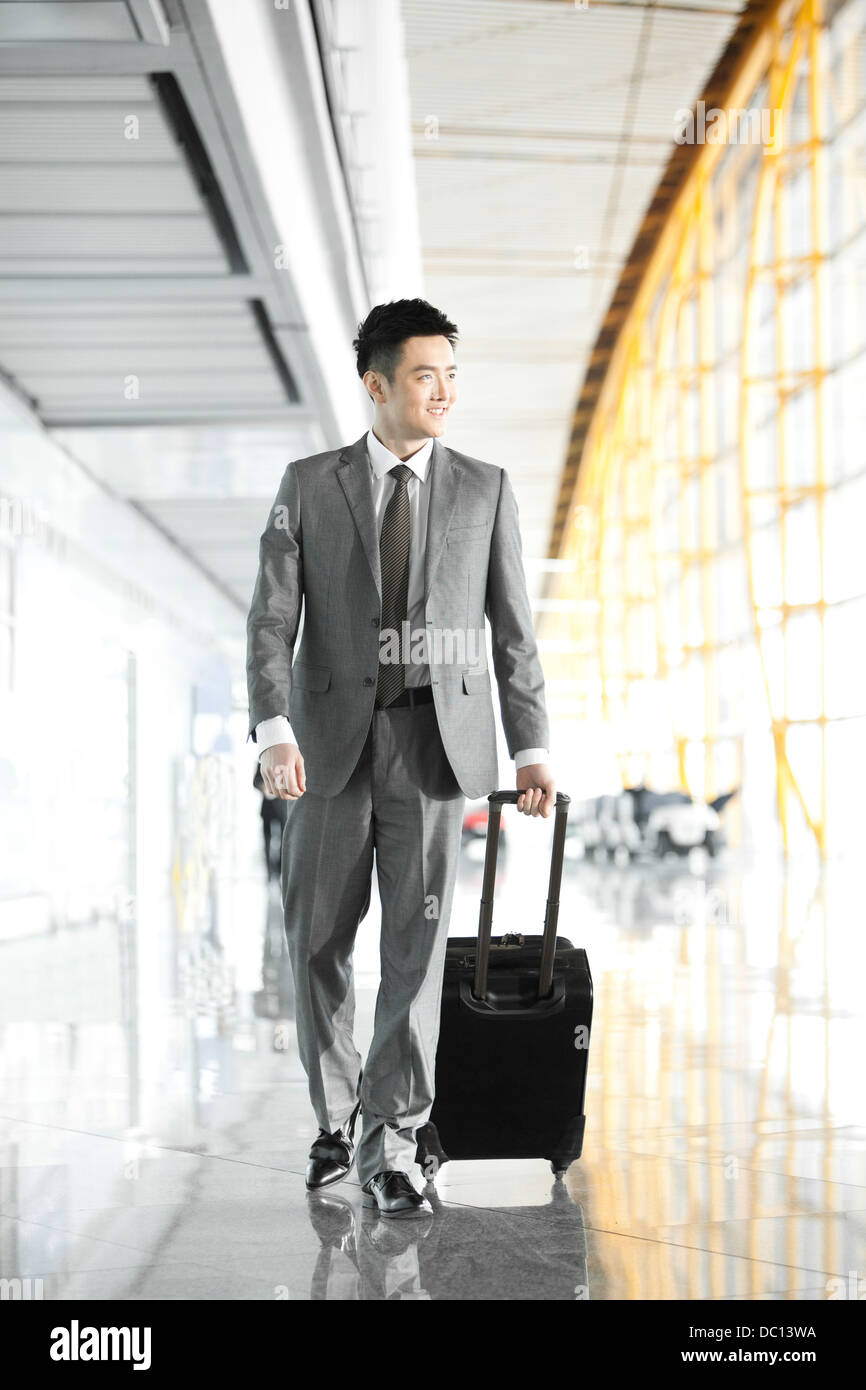 Businessman pulling wheeled luggage in airport lobby Stock Photo - Alamy