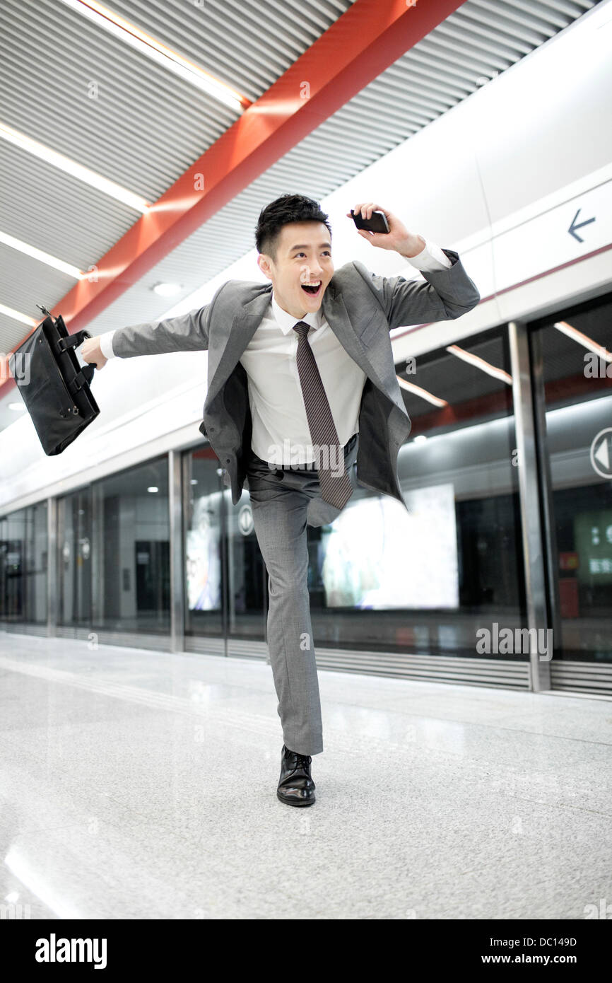 Excited businessman running at subway station Stock Photo - Alamy