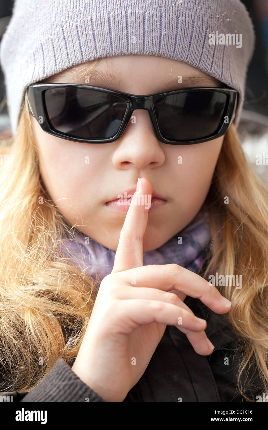 Little girl in sunglasses shows silence sign Stock Photo - Alamy