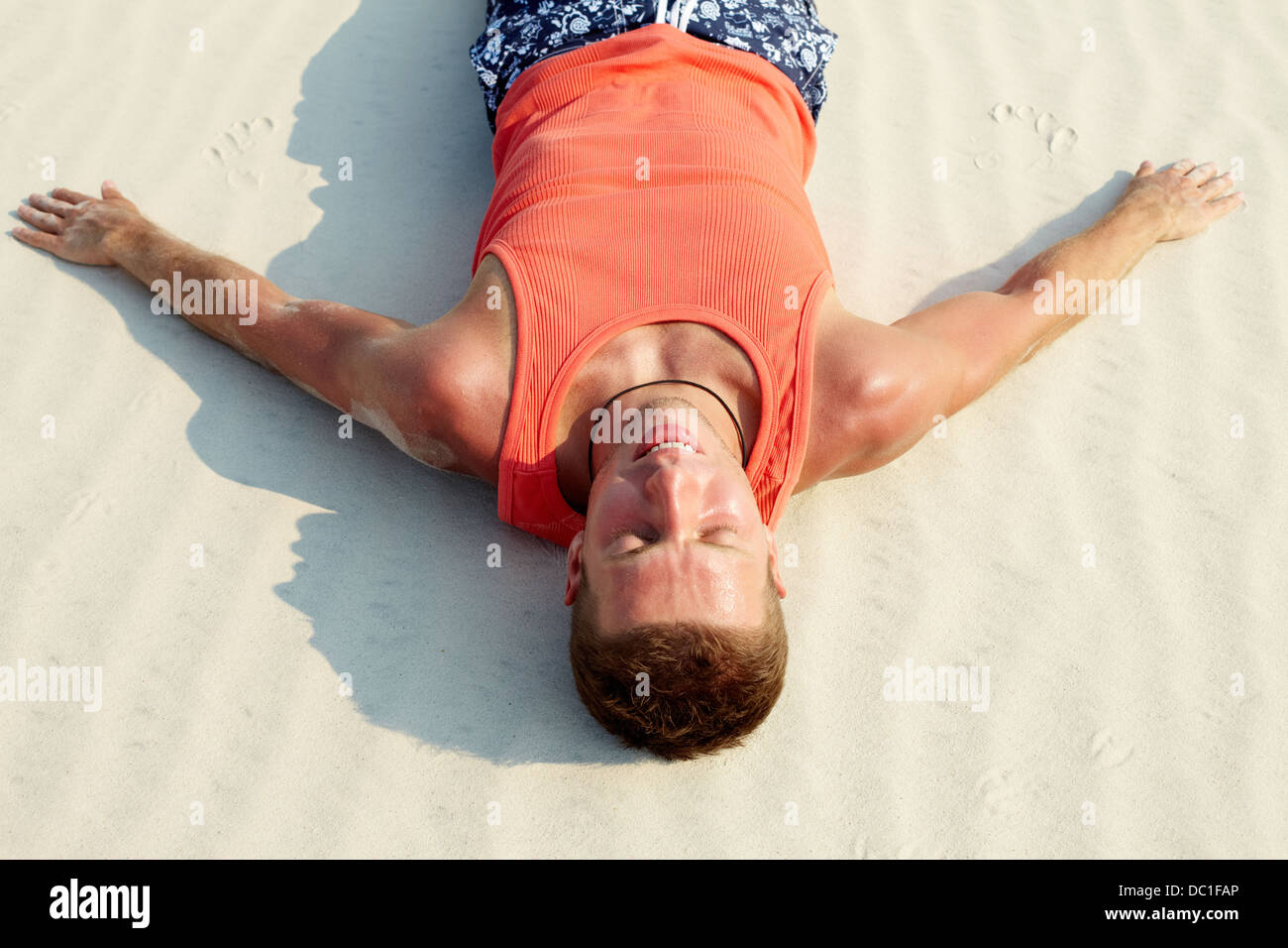 Image of a handsome guy in vest relaxing on sand Stock Photo - Alamy