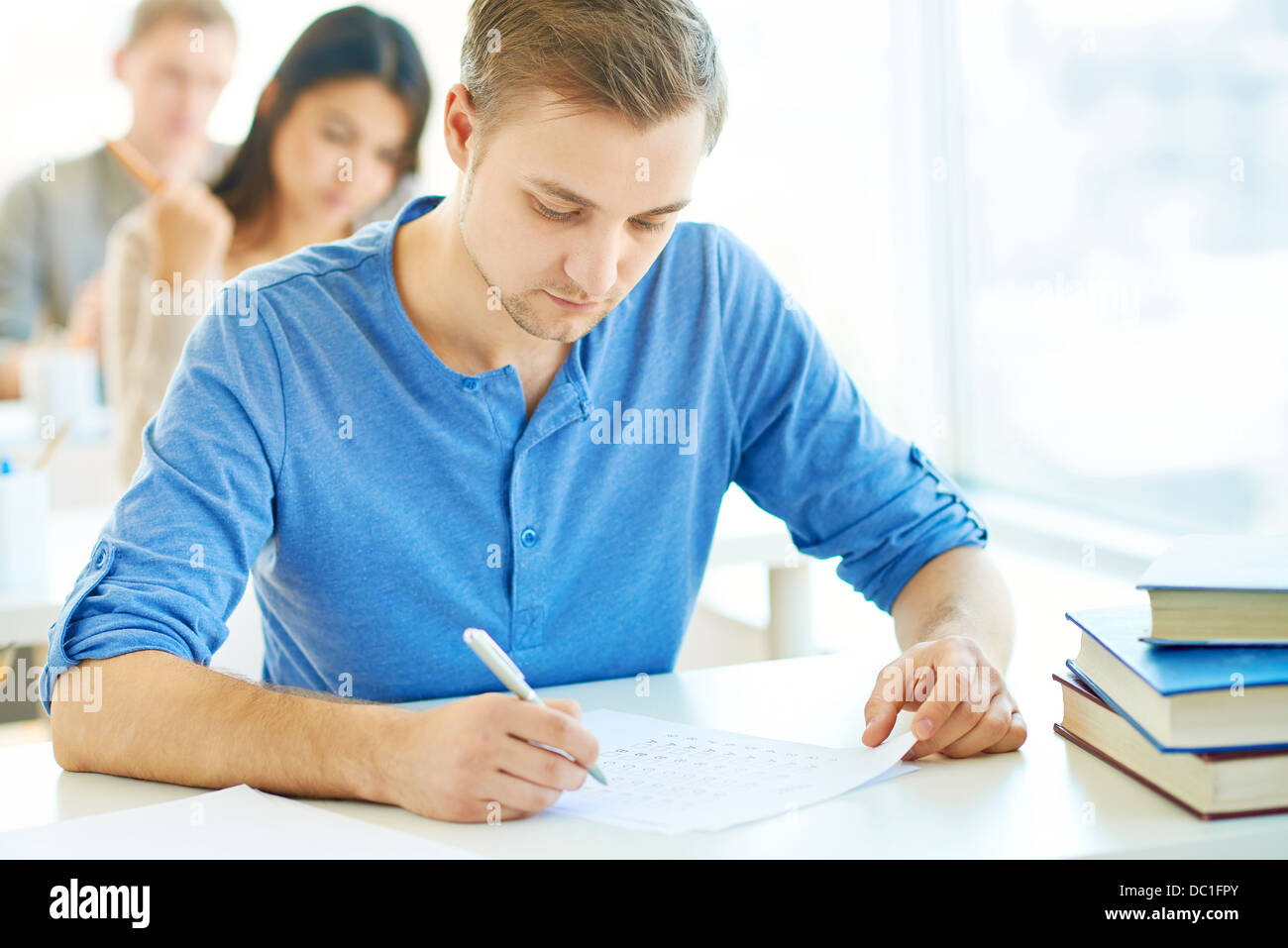 Portrait of handsome student carrying out test at lesson with ...