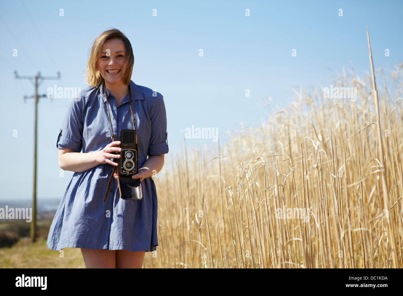 Portrait of young woman holding camera Stock Photo - Alamy