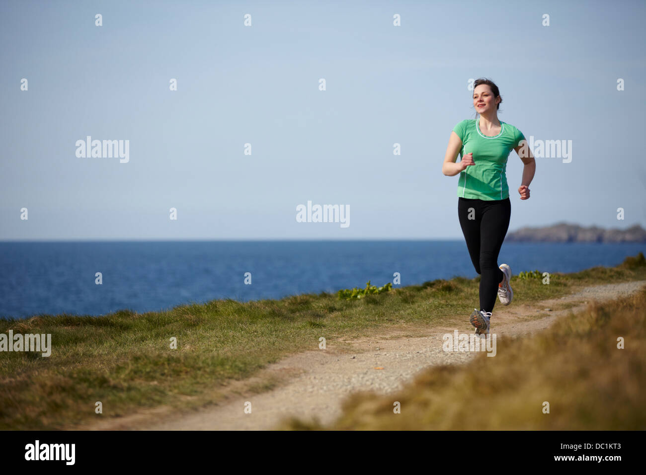 Young woman running along coastal path Stock Photo - Alamy