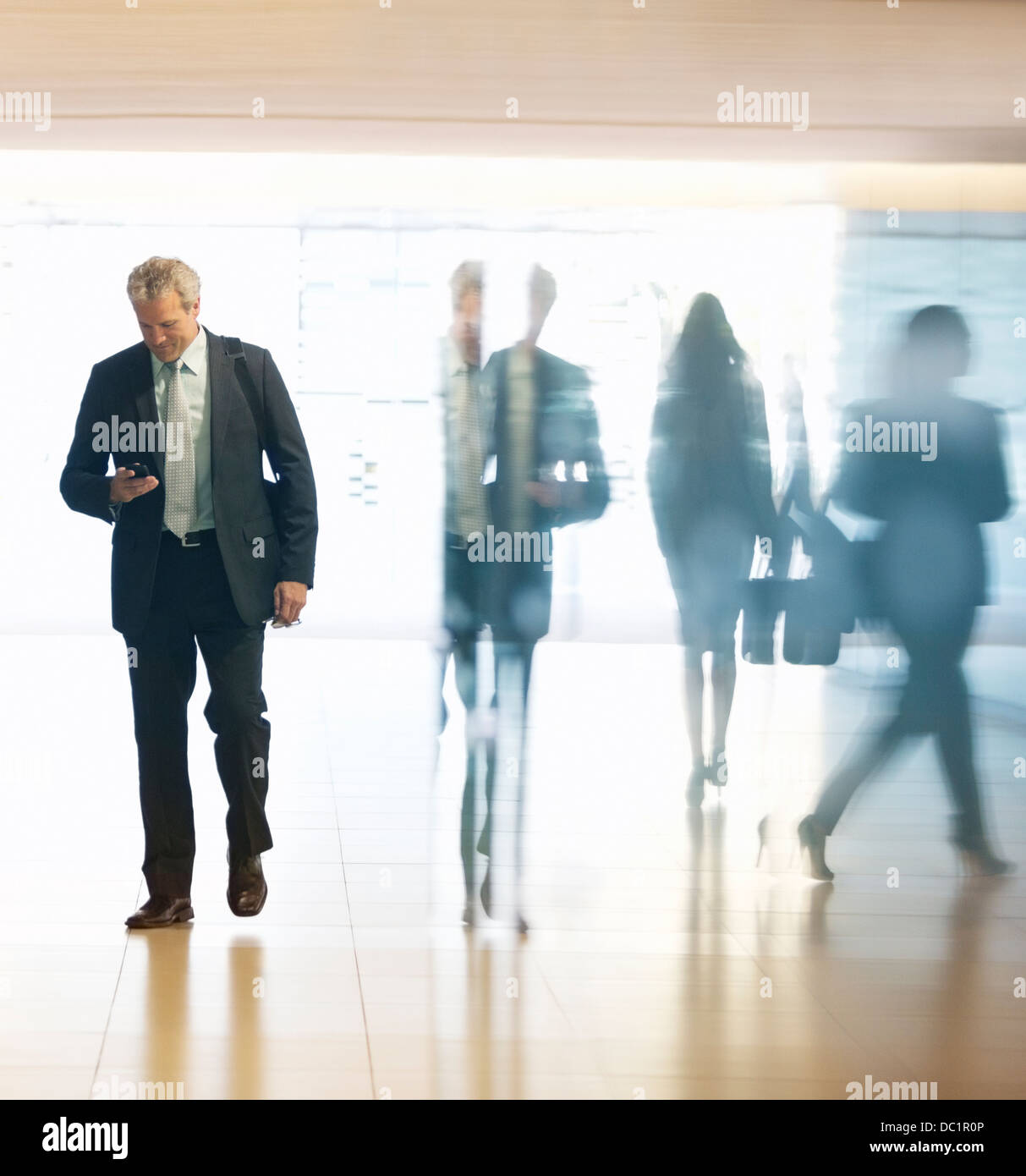 Businessman checking cell phone in lobby Stock Photo - Alamy