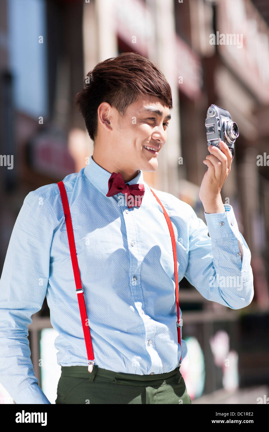 Fashionable young man shooting with a camera Stock Photo - Alamy