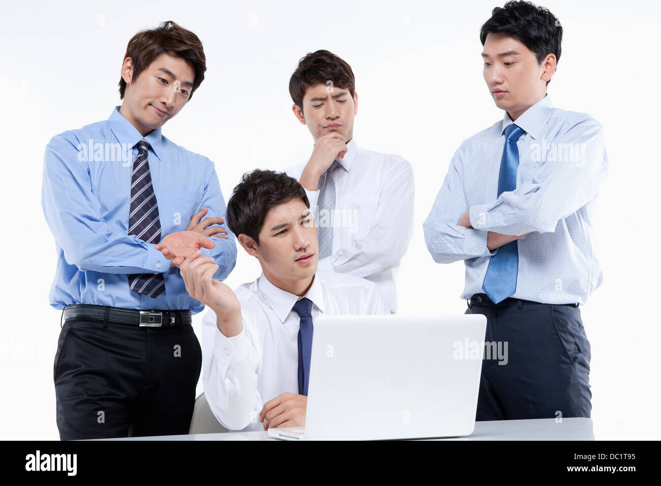 businessmen talking while standing around a colleague Stock Photo - Alamy