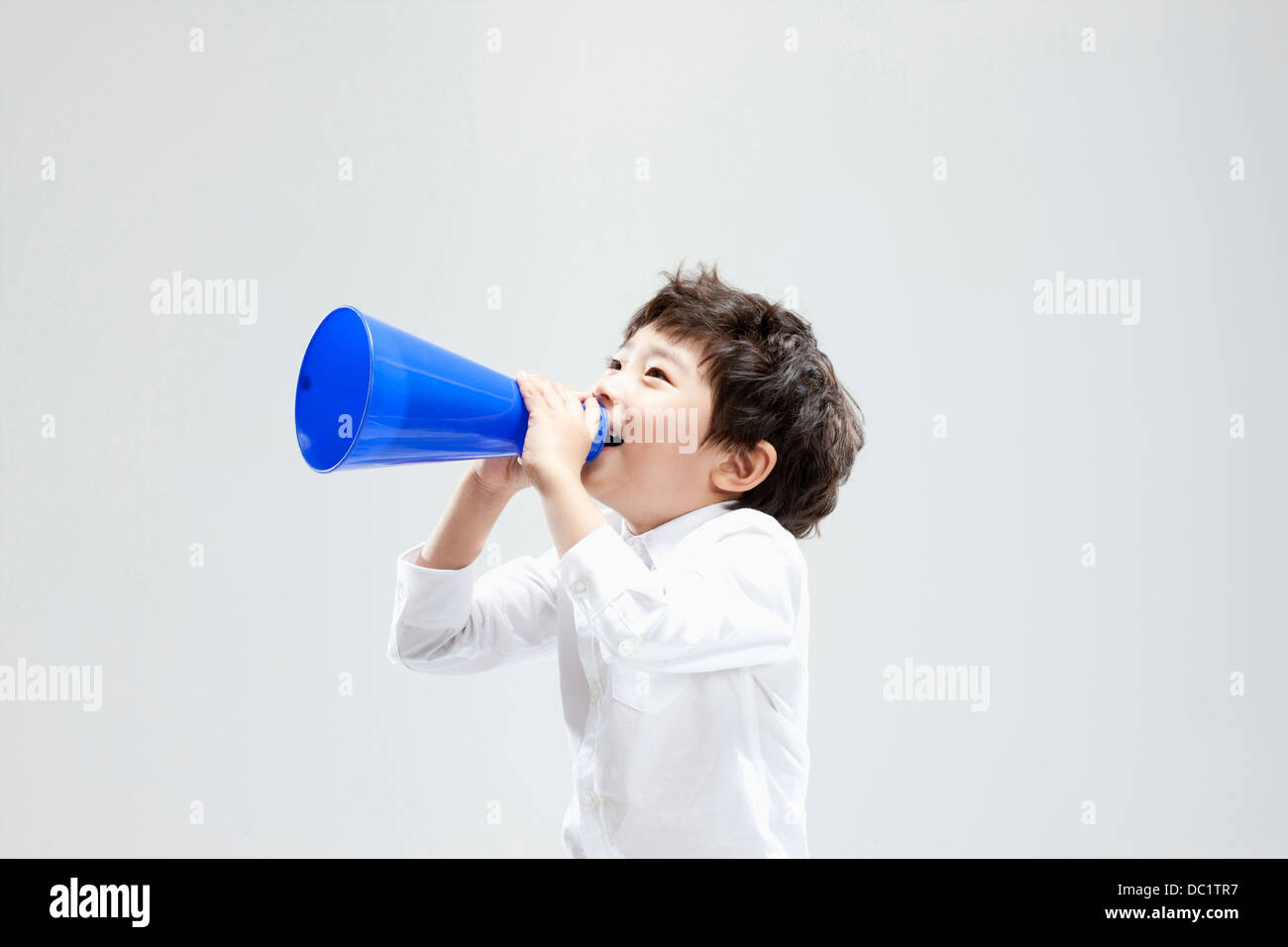 a boy shouting at blue megaphone Stock Photo - Alamy